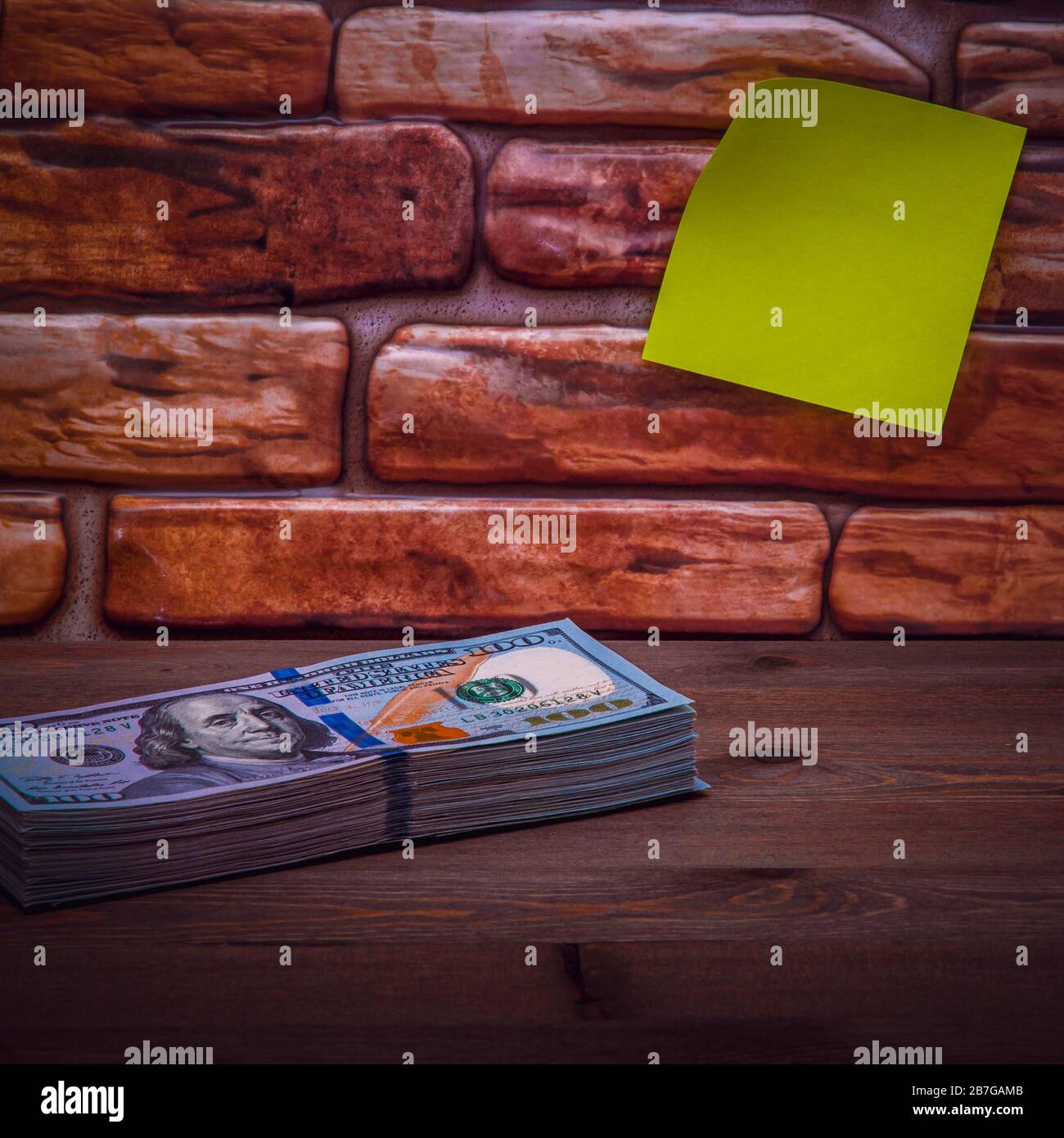 A stack of hundred-dollar bills against a brick wall and a note Stock ...