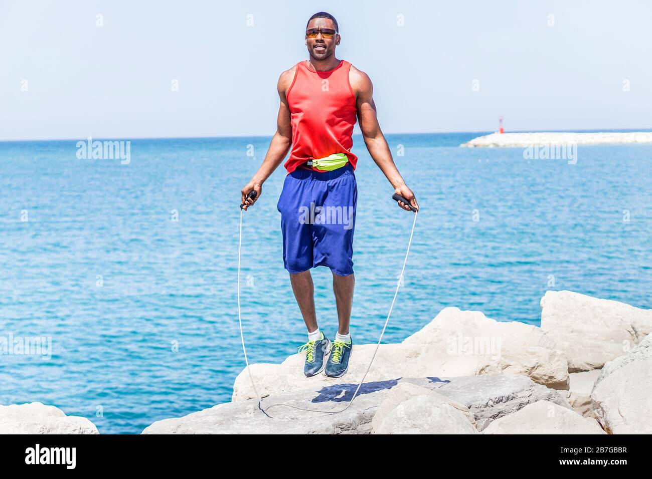 Black handsome man jumping rope with sea view in background - Male ...
