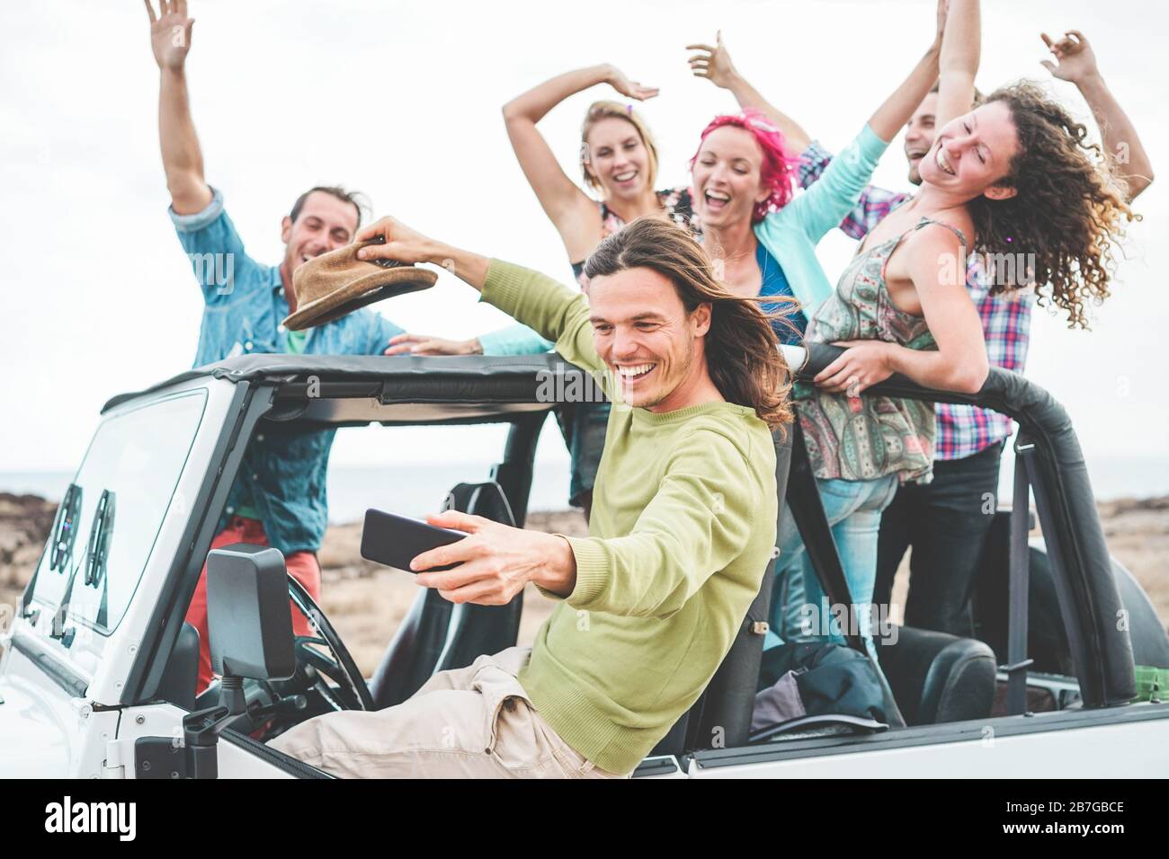 Group of happy friends doing excursion on desert in convertible 4x4 car ...