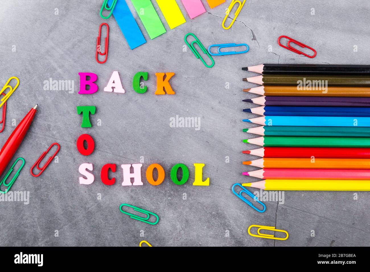 The layout of school supplies on a dark gray background. Top view, the ...