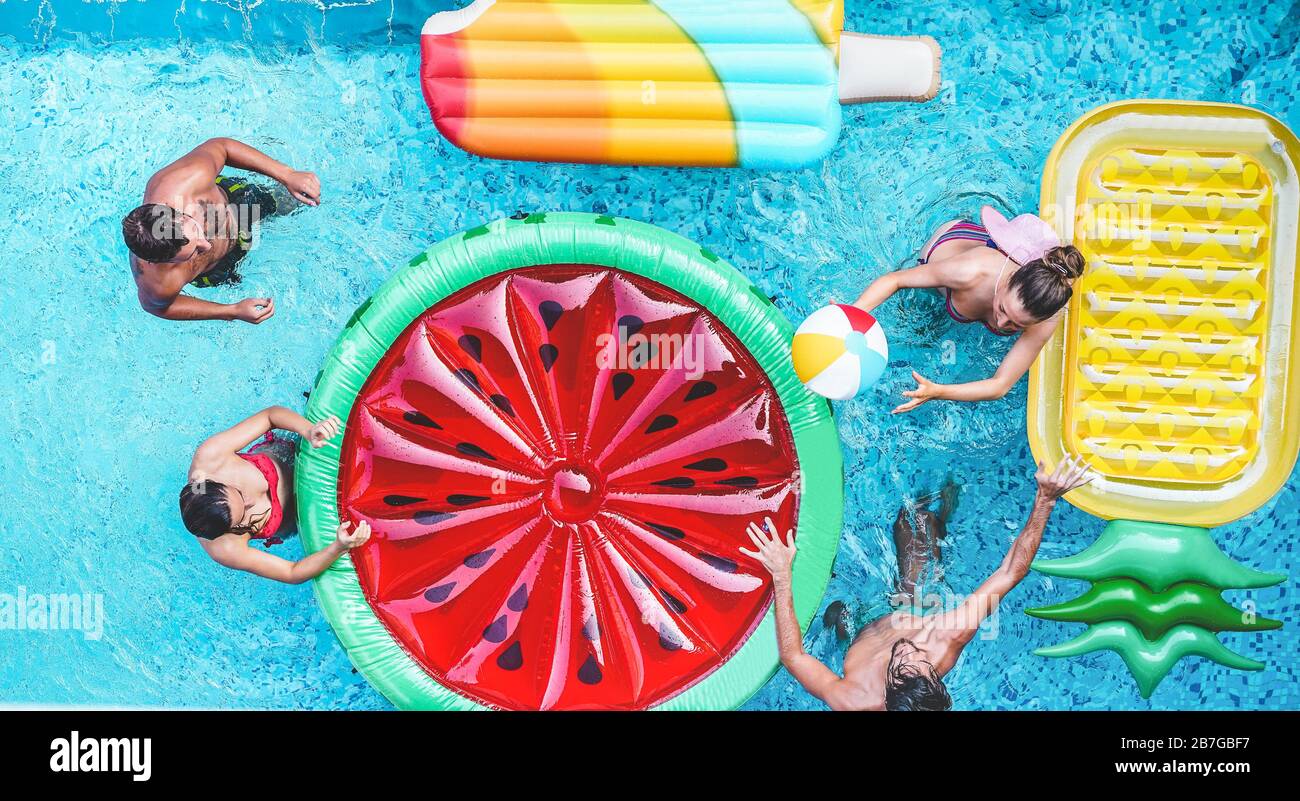 Happy friends playing with air lilo ball inside swimming pool - Young ...