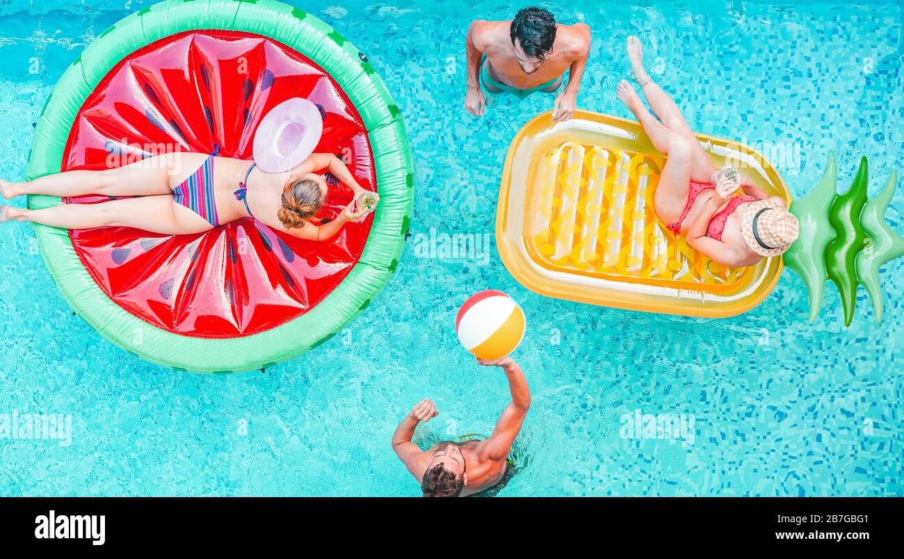 Happy friends playing with air lilo ball inside swimming pool - Young ...