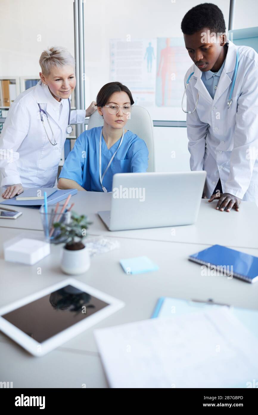 Multi-ethnic group of doctors using computer while working on medical ...