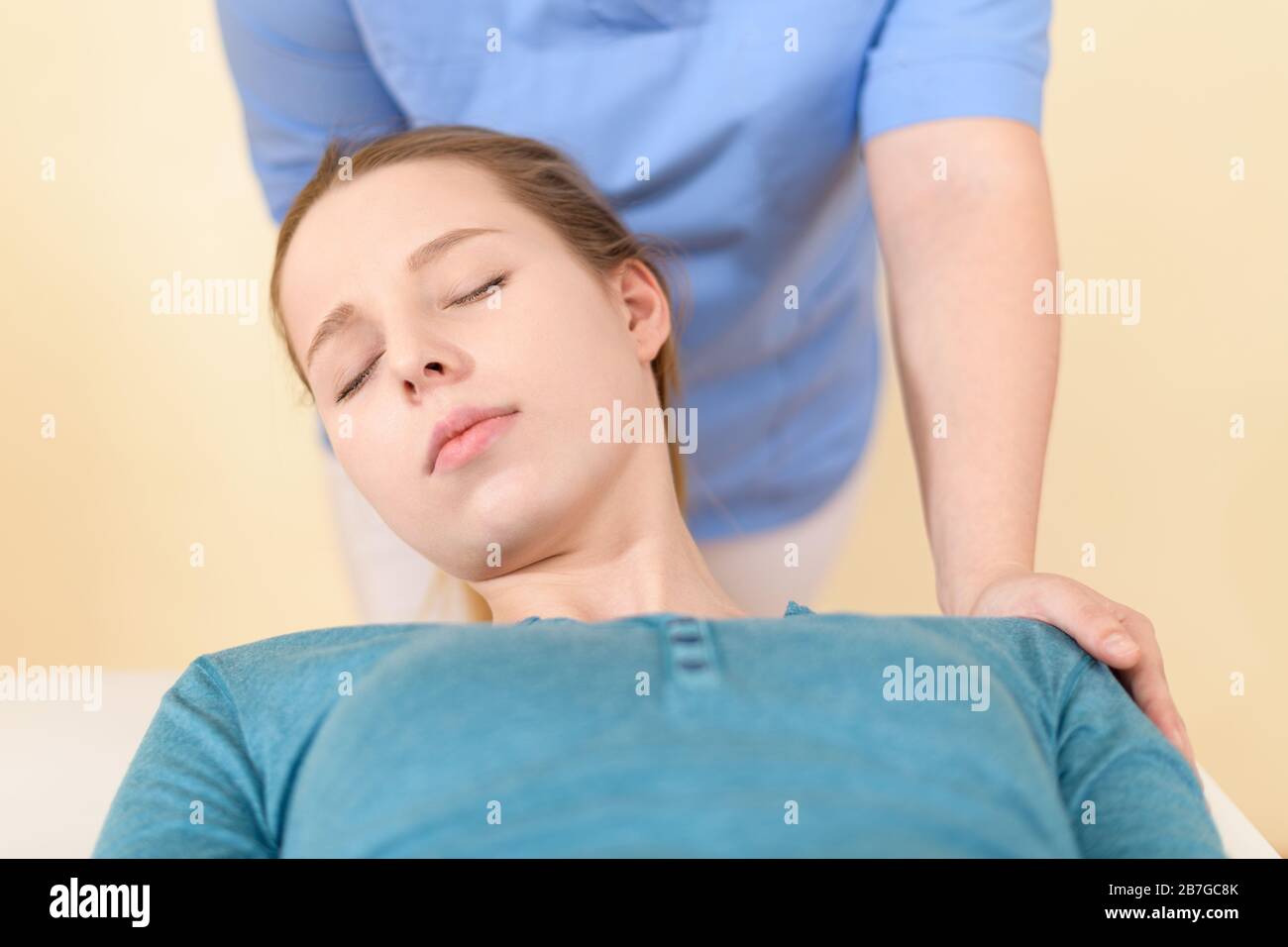 Female physiotherapist or a chiropractor adjusting patients neck ...