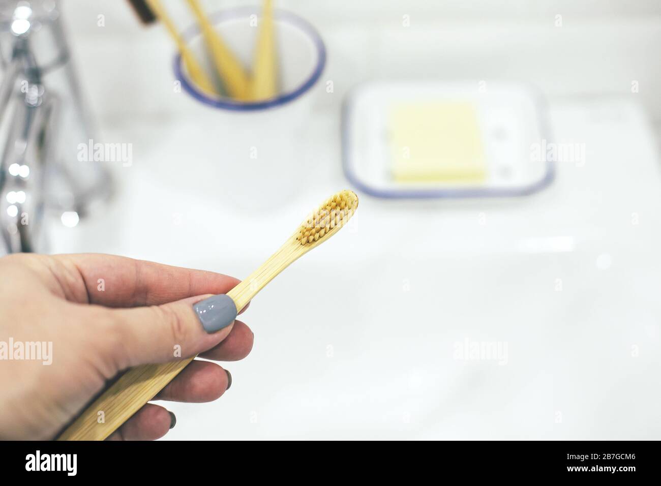 Bamboo wooden toothbrush in woman's hand in bathroom interior. No ...