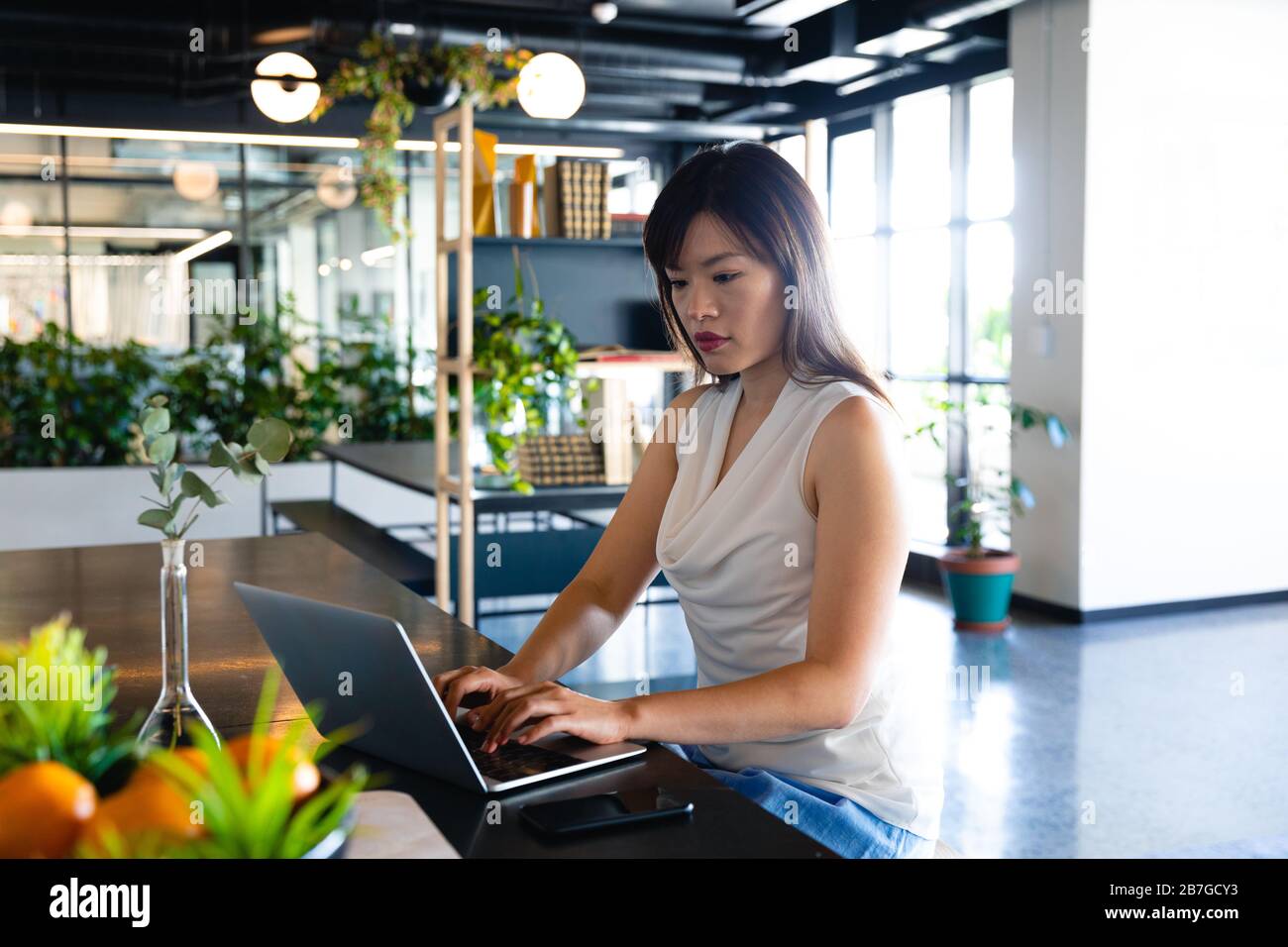 Asian woman working on her laptop in modern coworking zone Stock Photo ...