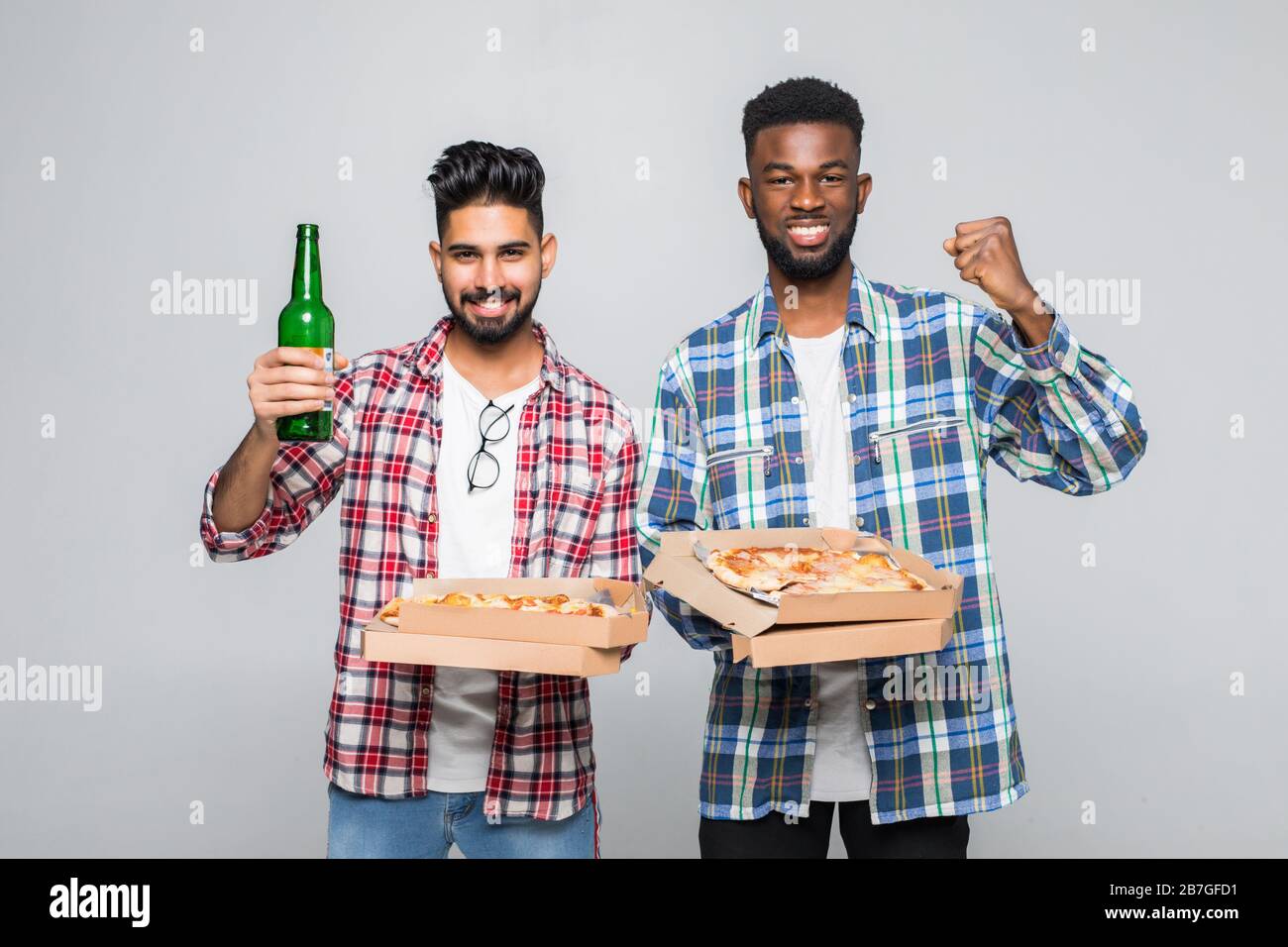 Portrait of two happy young men celebrating while holding beer bottles ...