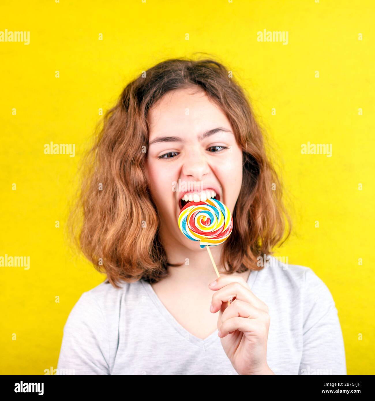 Teen girl angry bites multi-colored round lollipop Stock Photo - Alamy