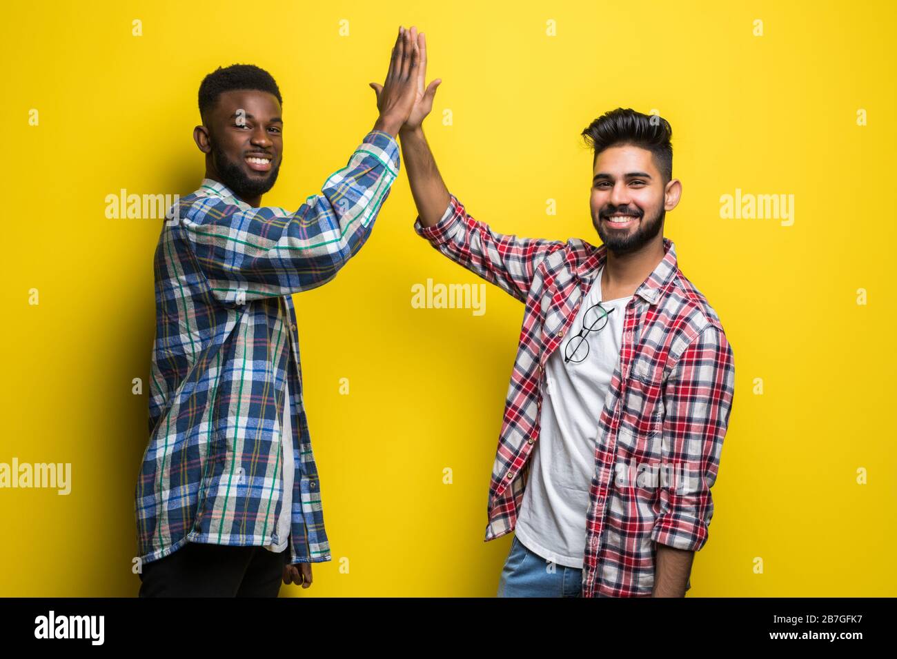 Portrait of a two delighted young men celebrating with high five ...