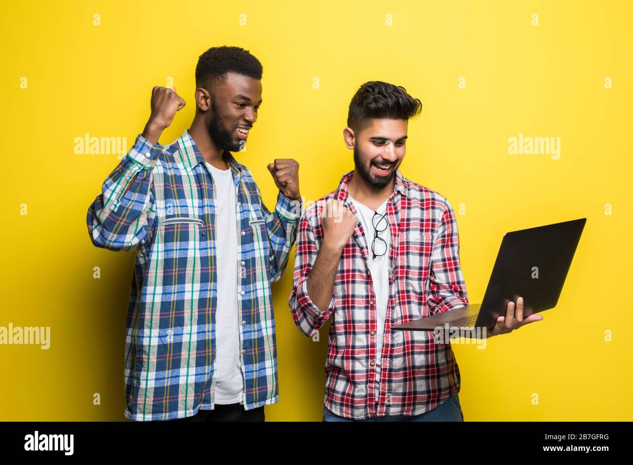 Portrait of a two happy young men holding laptop computer while ...