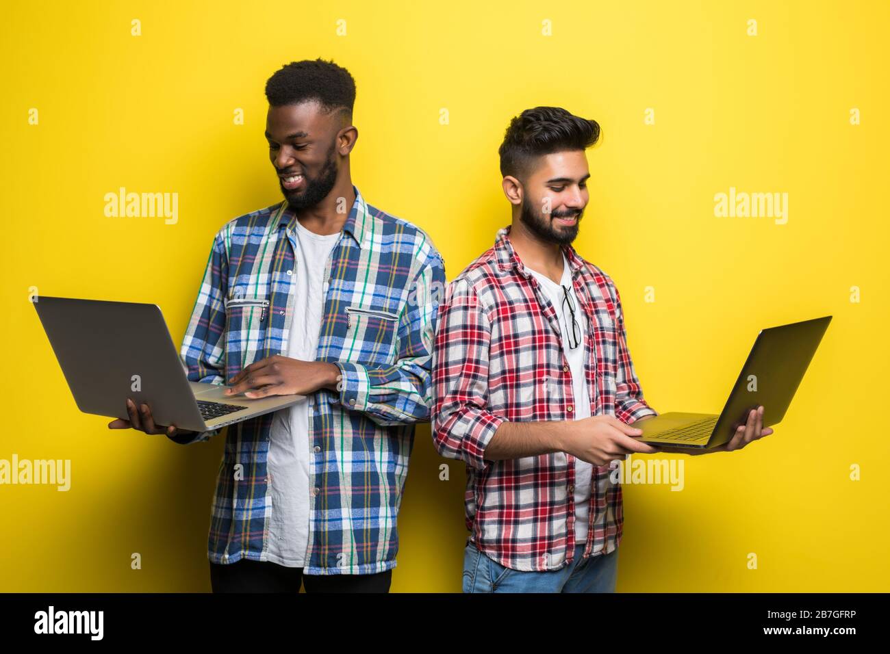 Portrait of a two happy young men holding laptop computer while ...