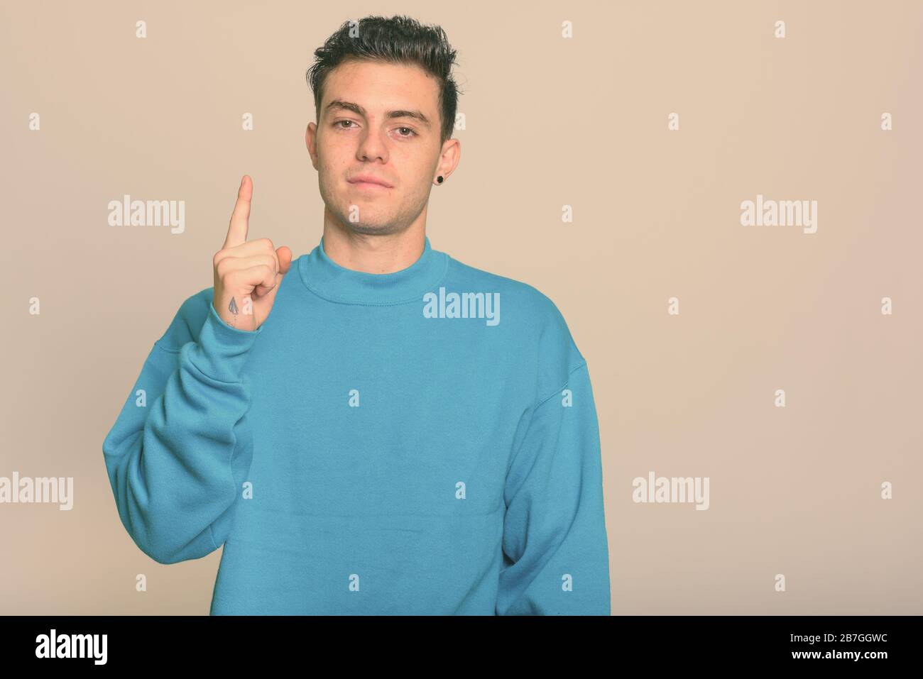 Studio shot of young man pointing finger up Stock Photo - Alamy