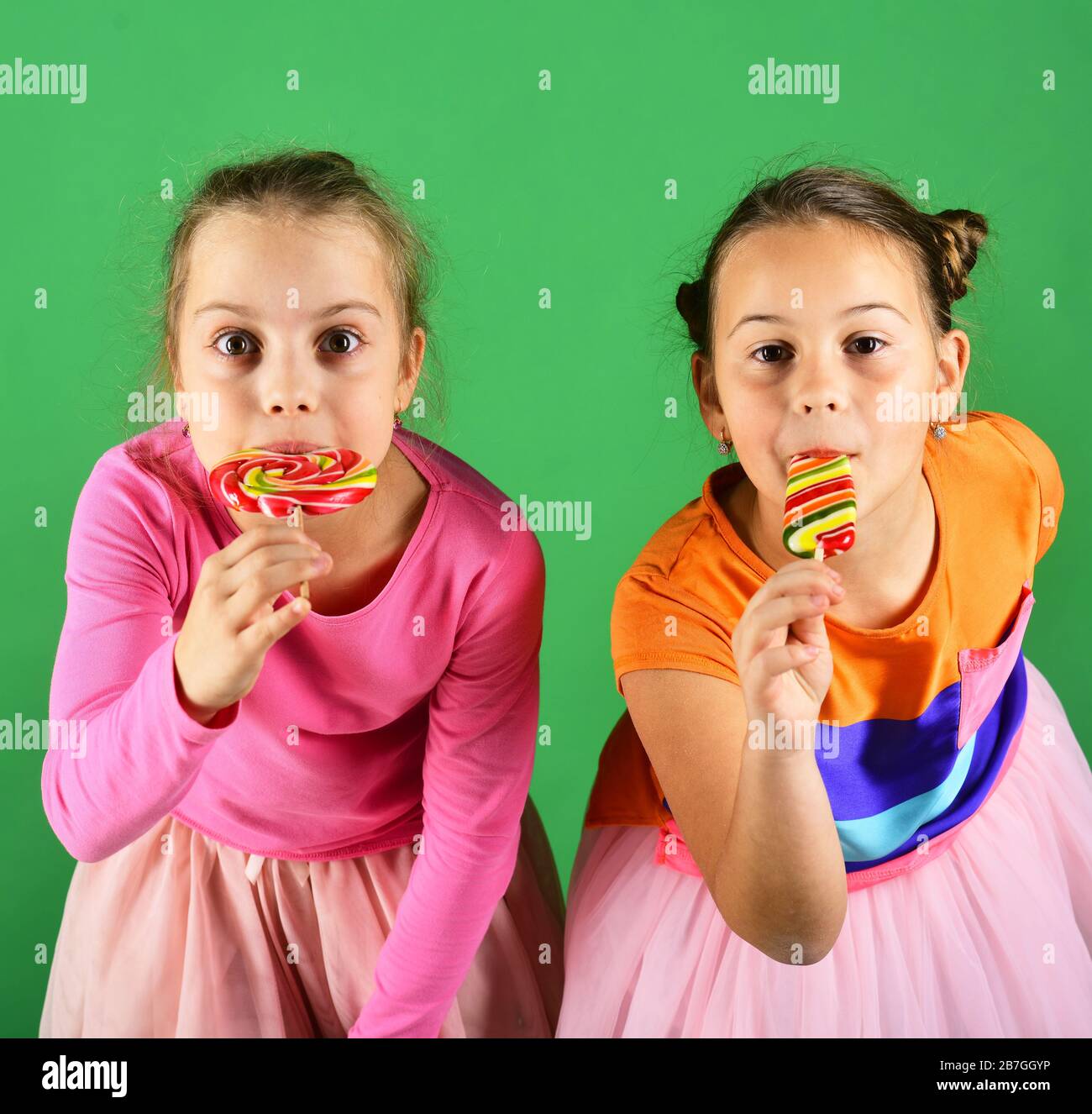 Happiness and dessert concept. Sisters with round and long shaped ...