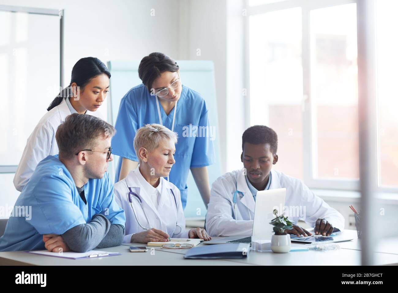 Multi-ethnic group of doctors looking at laptop screen while working ...