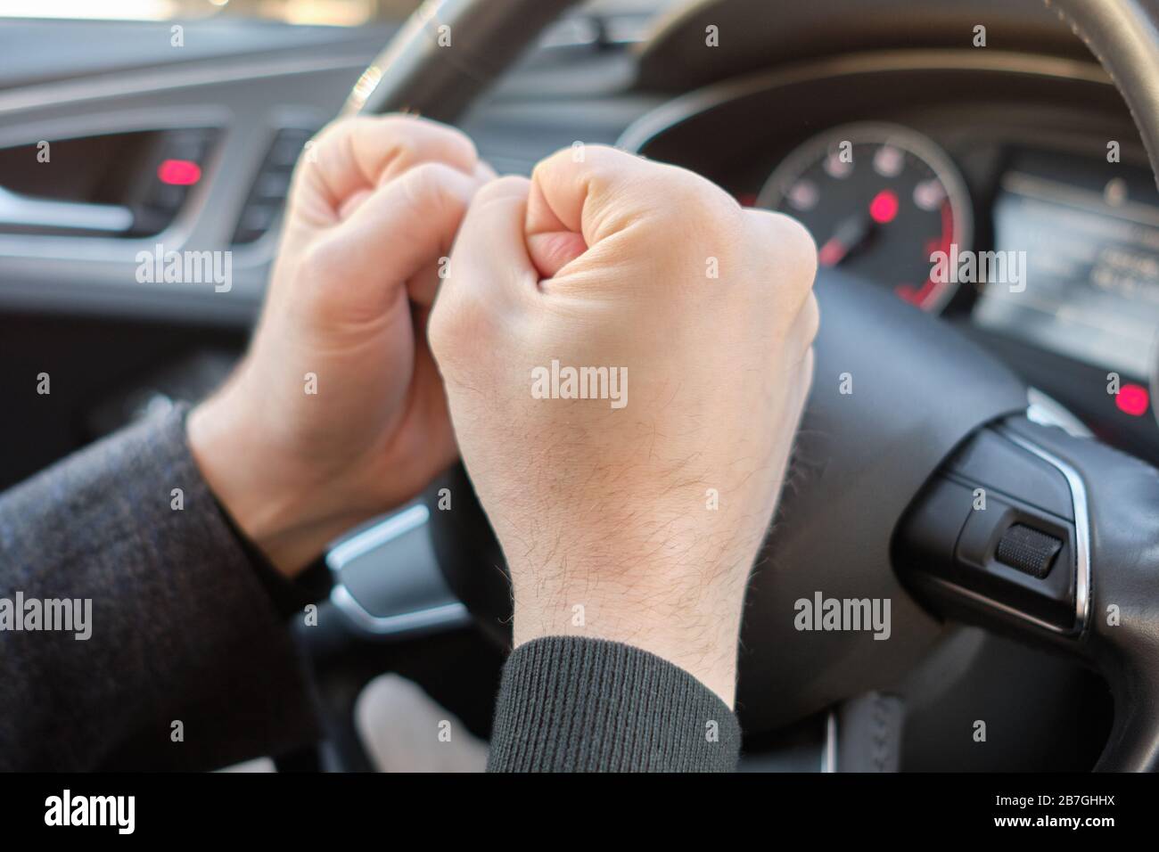 A man in a modern car. Hands hitting the steering wheel with anger ...