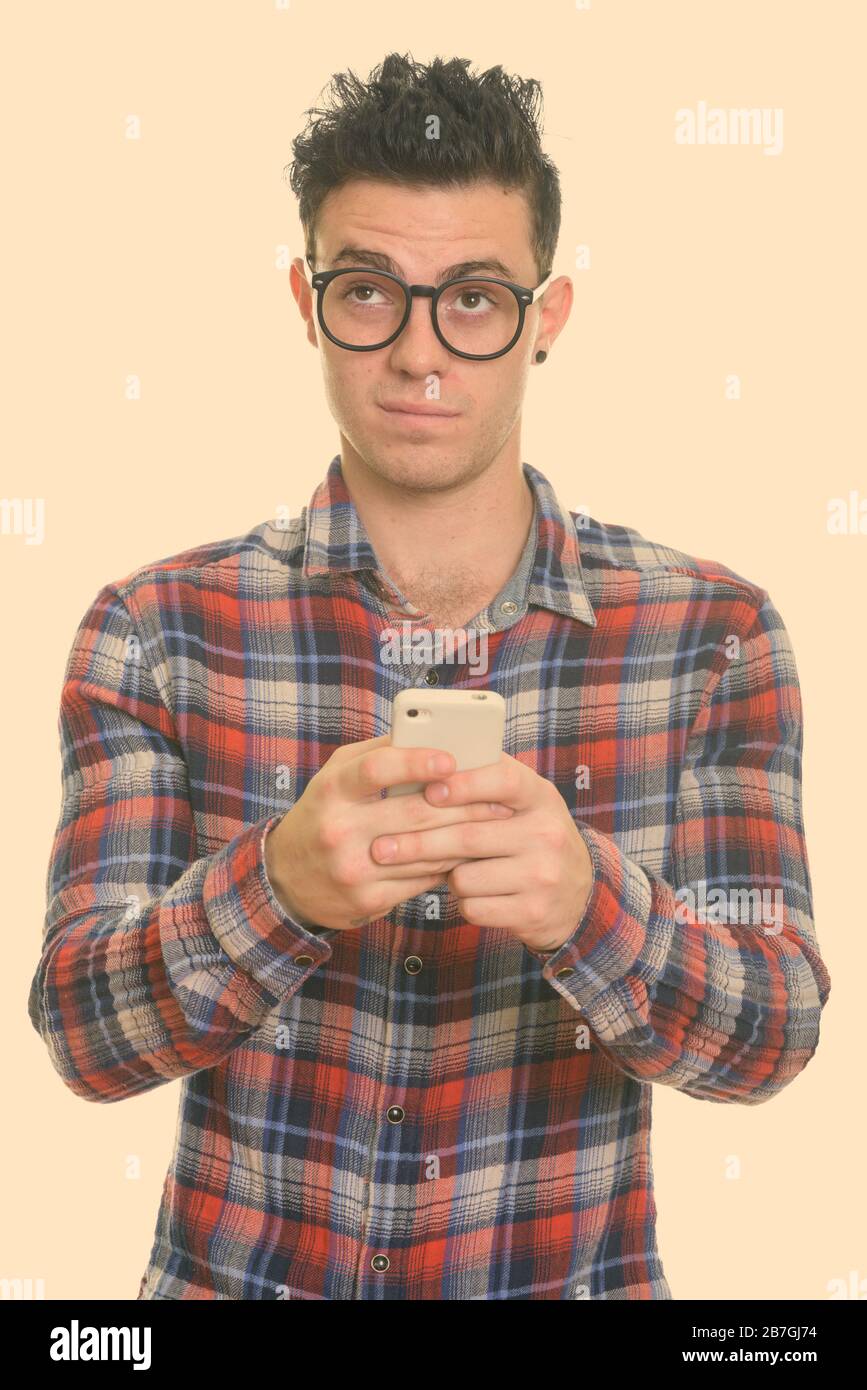 Studio shot of young man using mobile phone while thinking Stock Photo ...