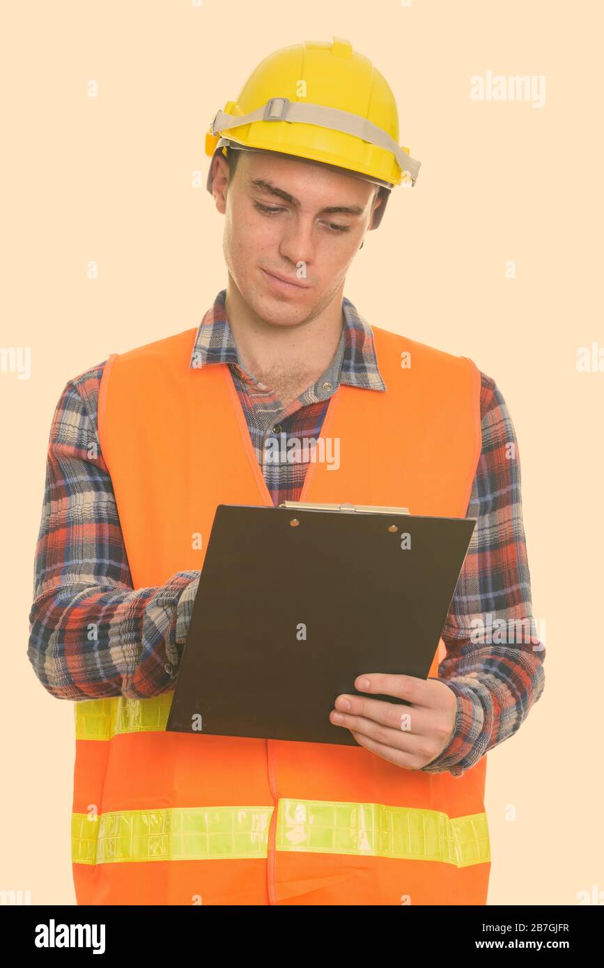 Studio shot of young man construction worker reading on clipboard Stock ...