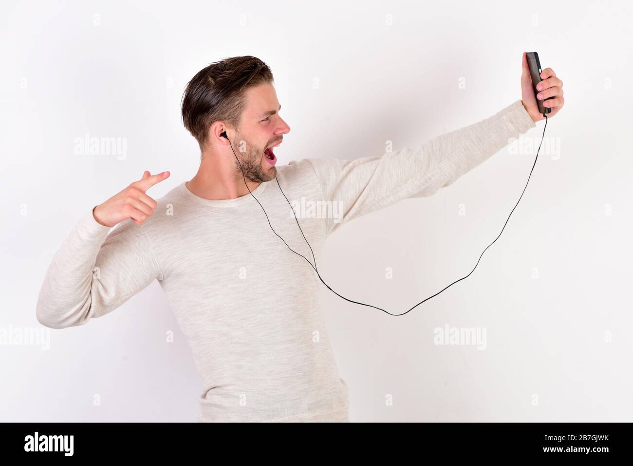 Entertainment and music concept. Guy with beard holds phone or MP3 ...