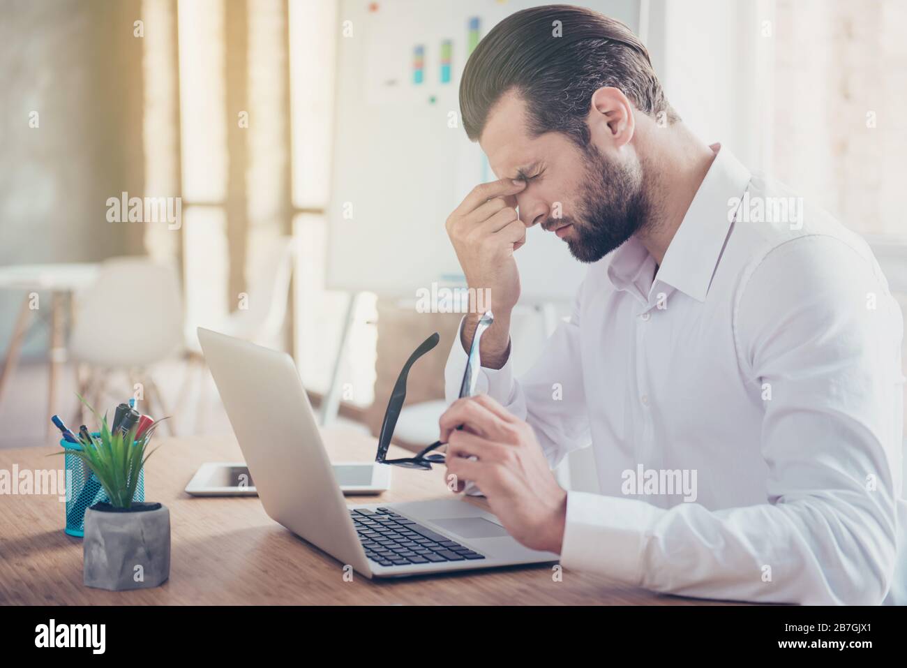 Overworked young man having headache after hard working day and ...