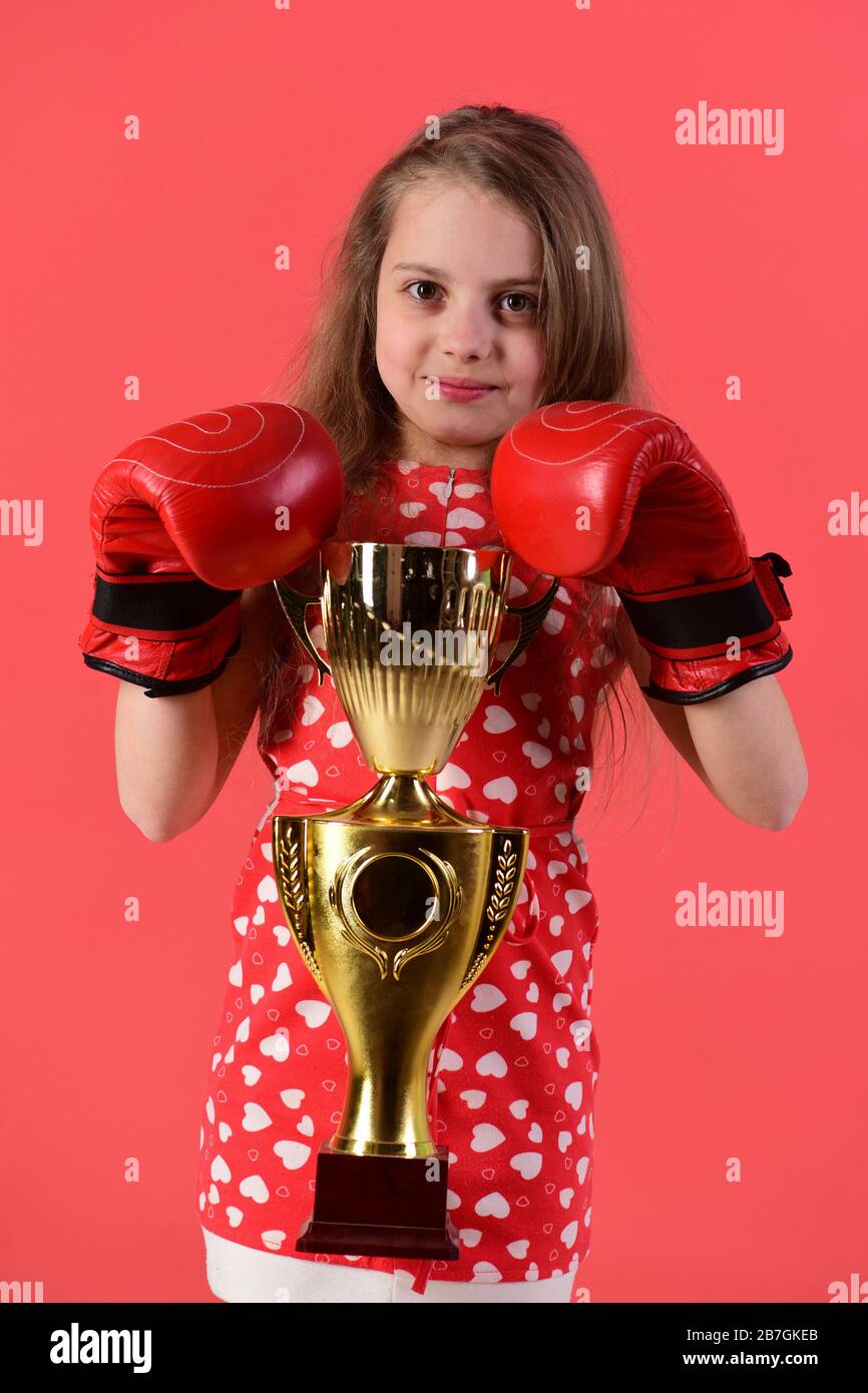 Kid in boxing gloves pose at trophy cup on red background. Girl power ...