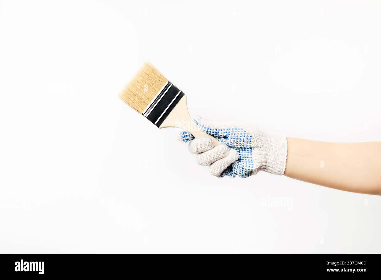 A woman 's hand in a construction glove holding a construction brush ...