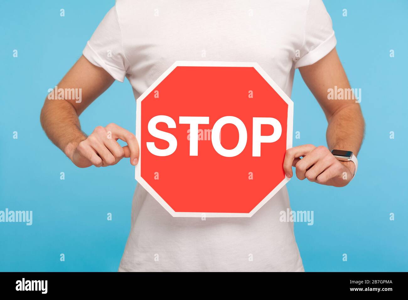 Closeup of man in white t-shirt holding Stop symbol in hands, warning ...