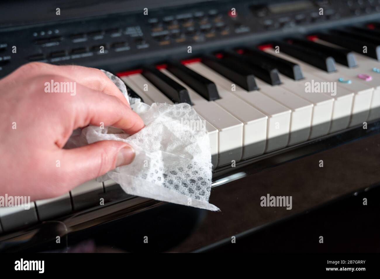 Caucasian hand holding a disinfectant wipe to sanitize piano keys Stock ...