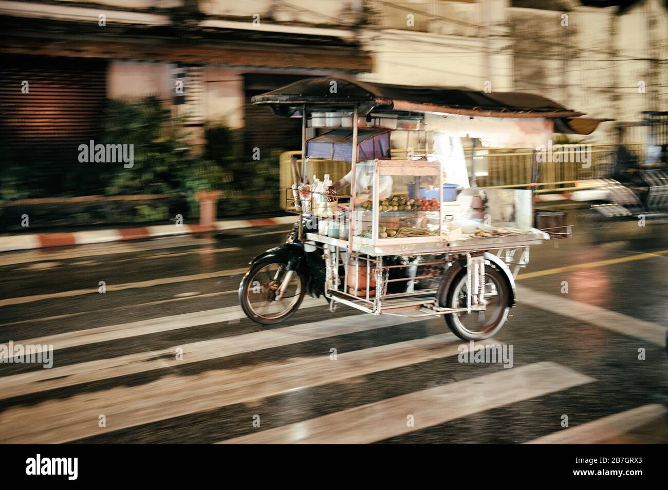 Thai street food vendor riding tricycle at rainy season at night in ...