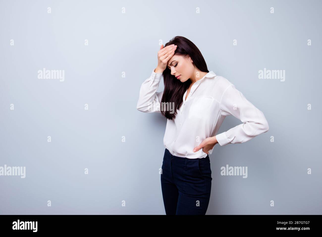 Young sad female worker touching her forehead because of having ...