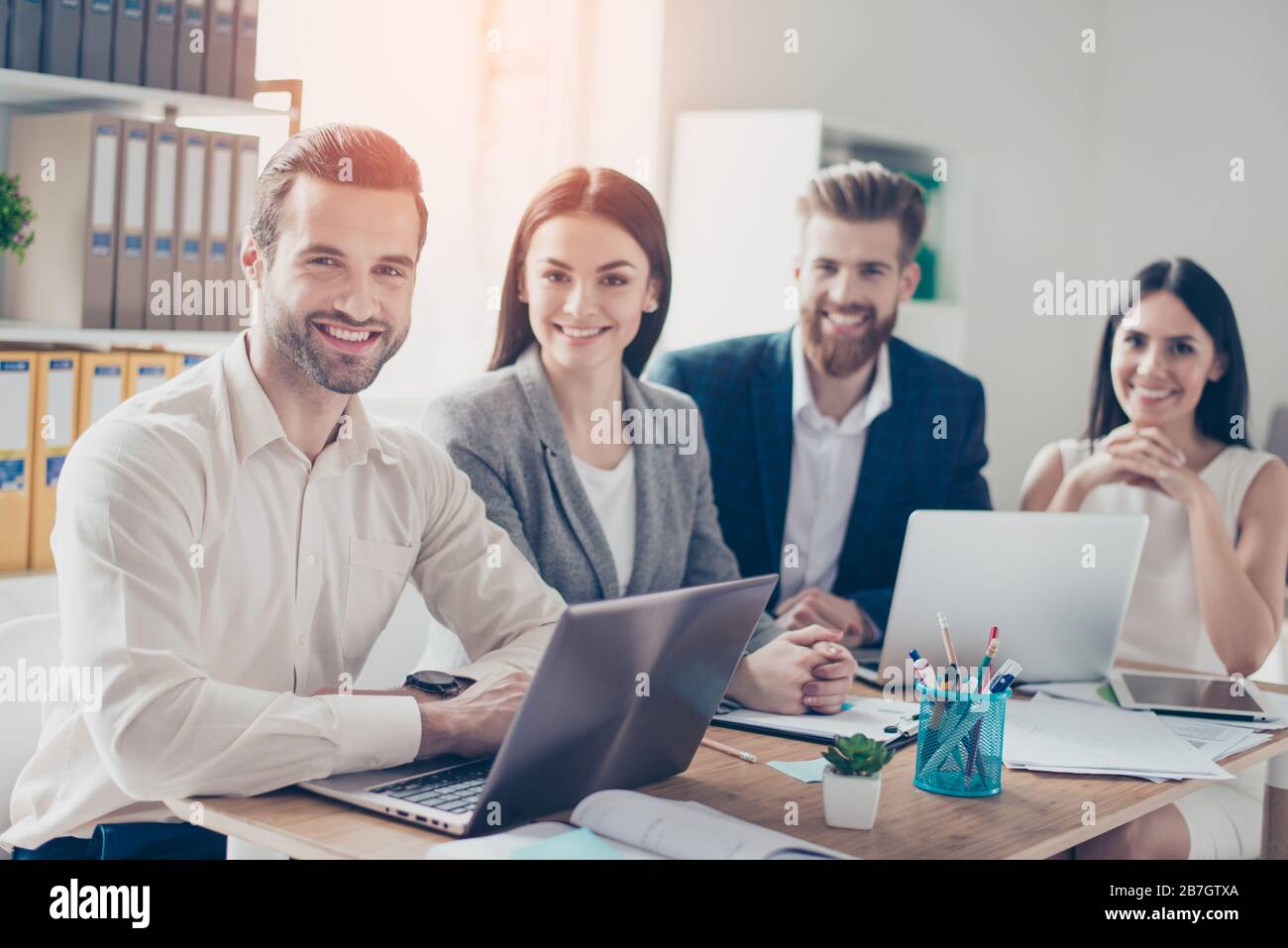 Close up of four successful young office workers looking straight and ...