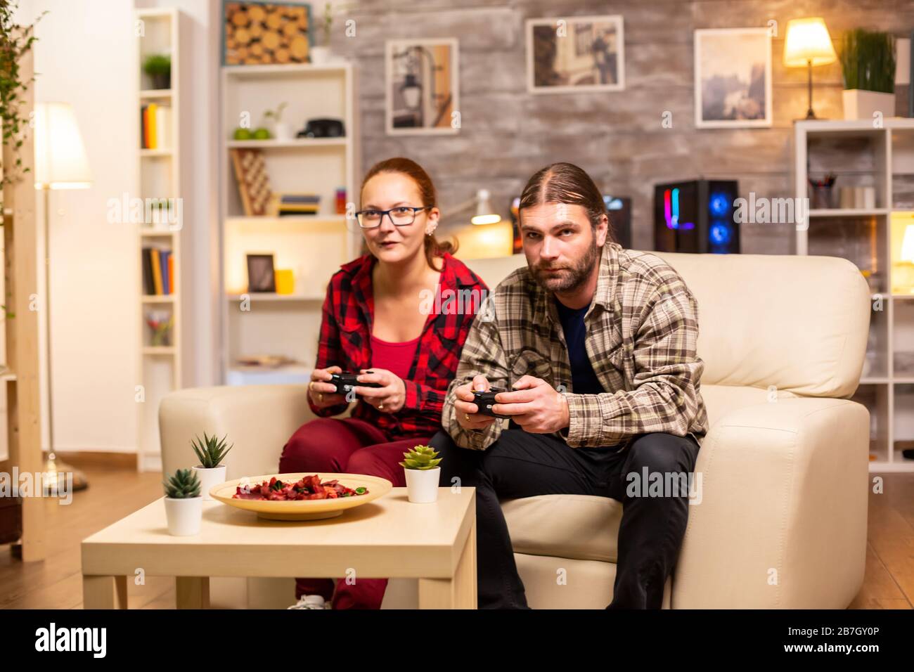 Gamers couple playing video games on the TV with wireless controllers ...