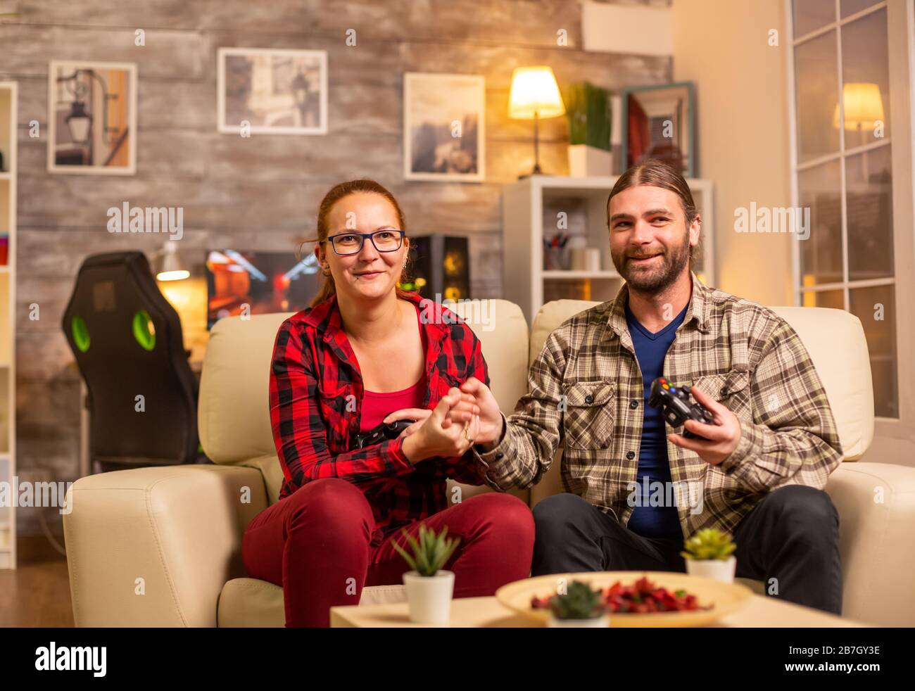Gamers couple playing video games on the TV with wireless controllers ...