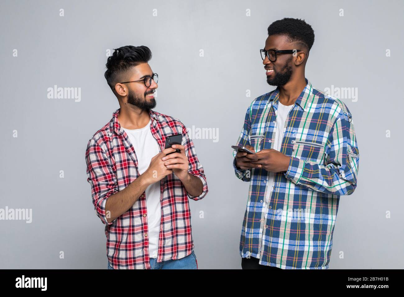Portrait of a two happy young men using mobile phones Stock Photo - Alamy