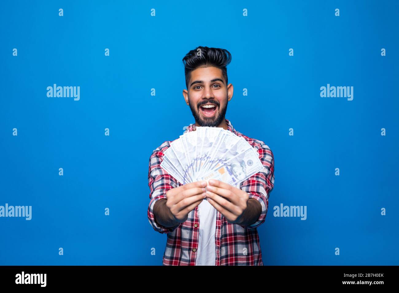 Portrait of handsome young man showing money banknotes standing over ...