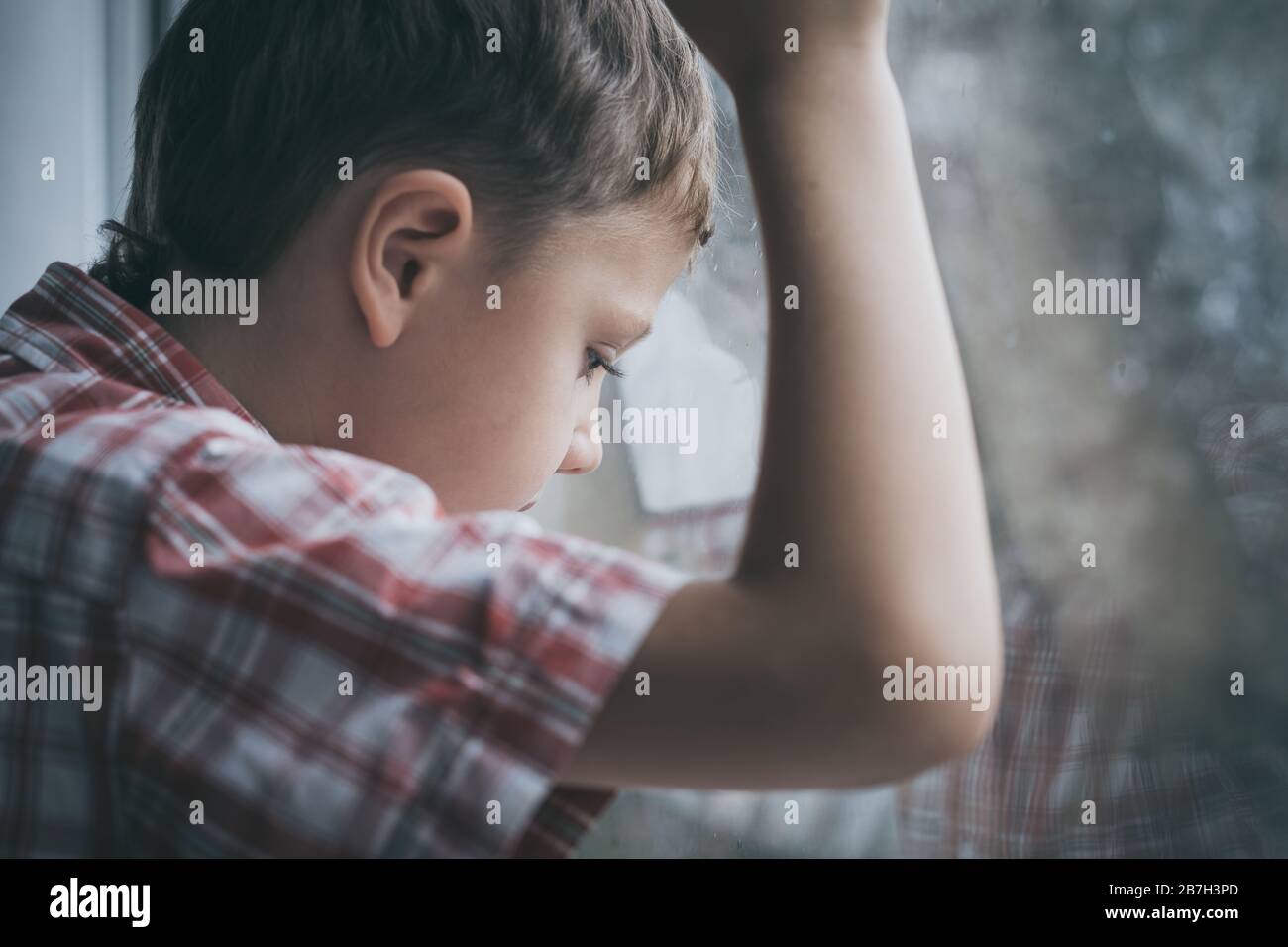 portrait one sad little boy sitting near a window at the day time Stock ...