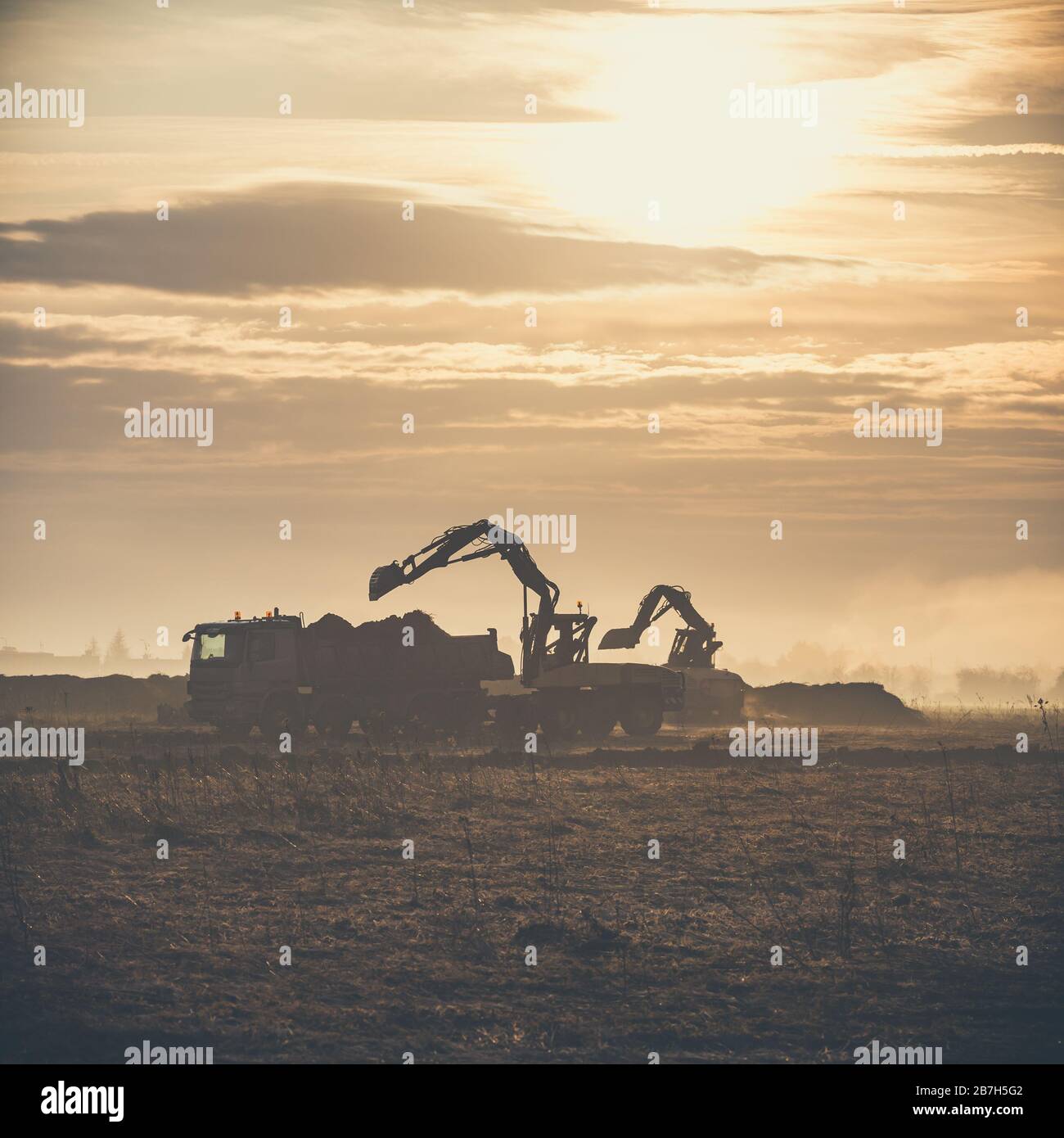 Excavator working on construction site, loading a dump track at sunrise ...