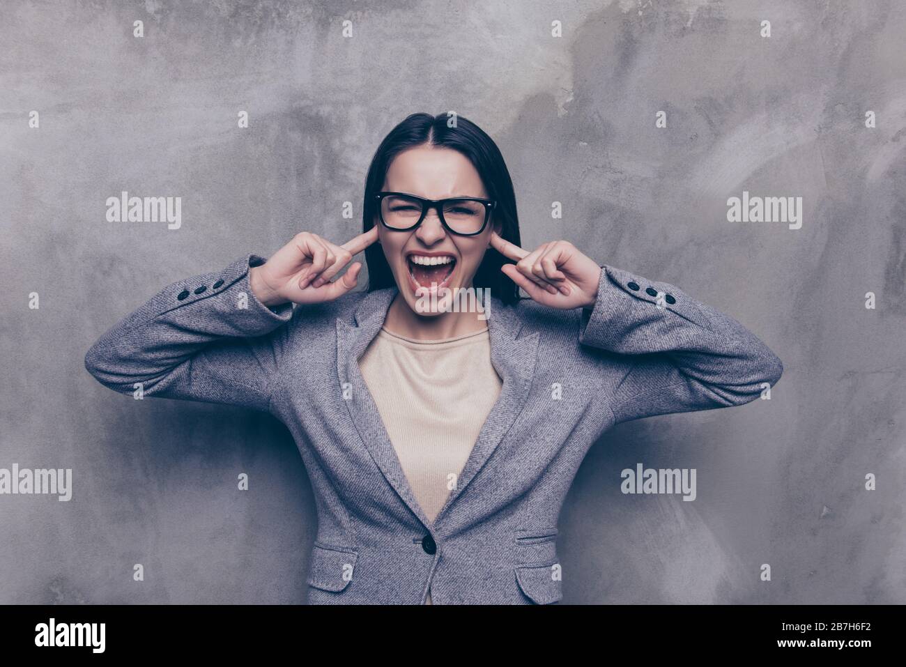 Portrait of uncontrollable mad girl screaming and closing her ears with ...