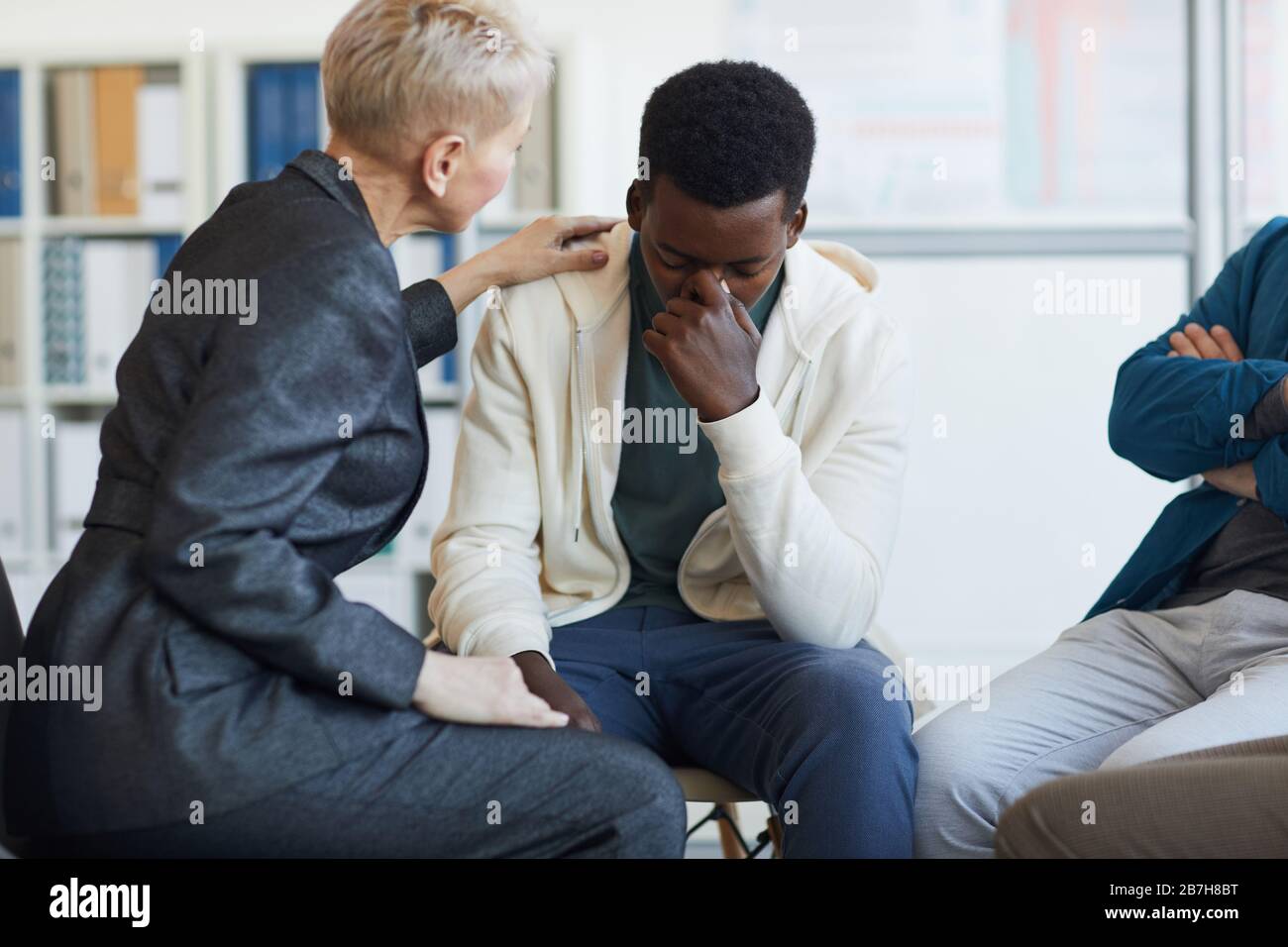 Portrait of young African-American man crying while sitting on chair in ...