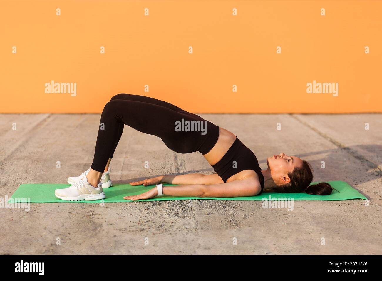 Fit athletic girl in tight sportswear, black pants and top, practicing ...