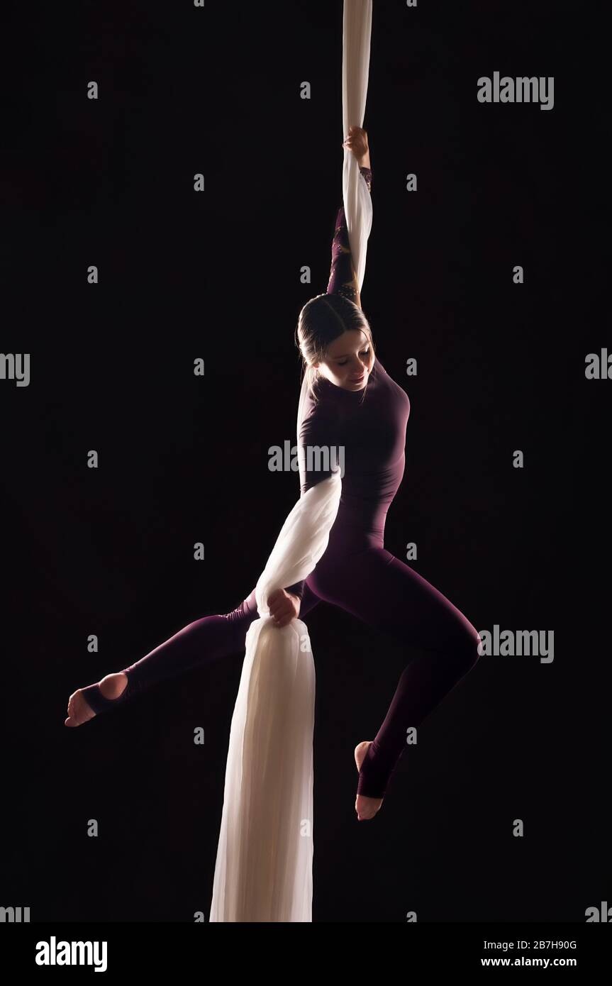 Sporty woman in a Burgundy suit performs gymnastic and circus exercises ...