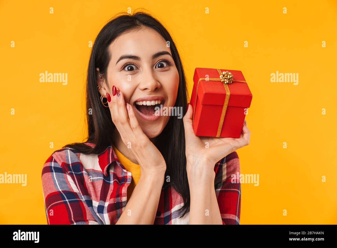 Photo of delighted young woman expressing surprise and holding gift box ...