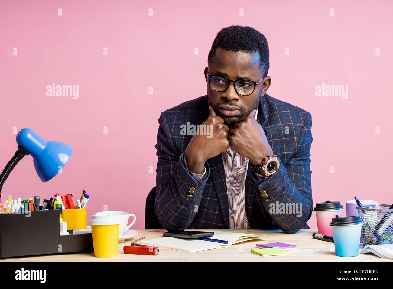 Portrait of tired unhappy young dark skinned manager sitting at ...