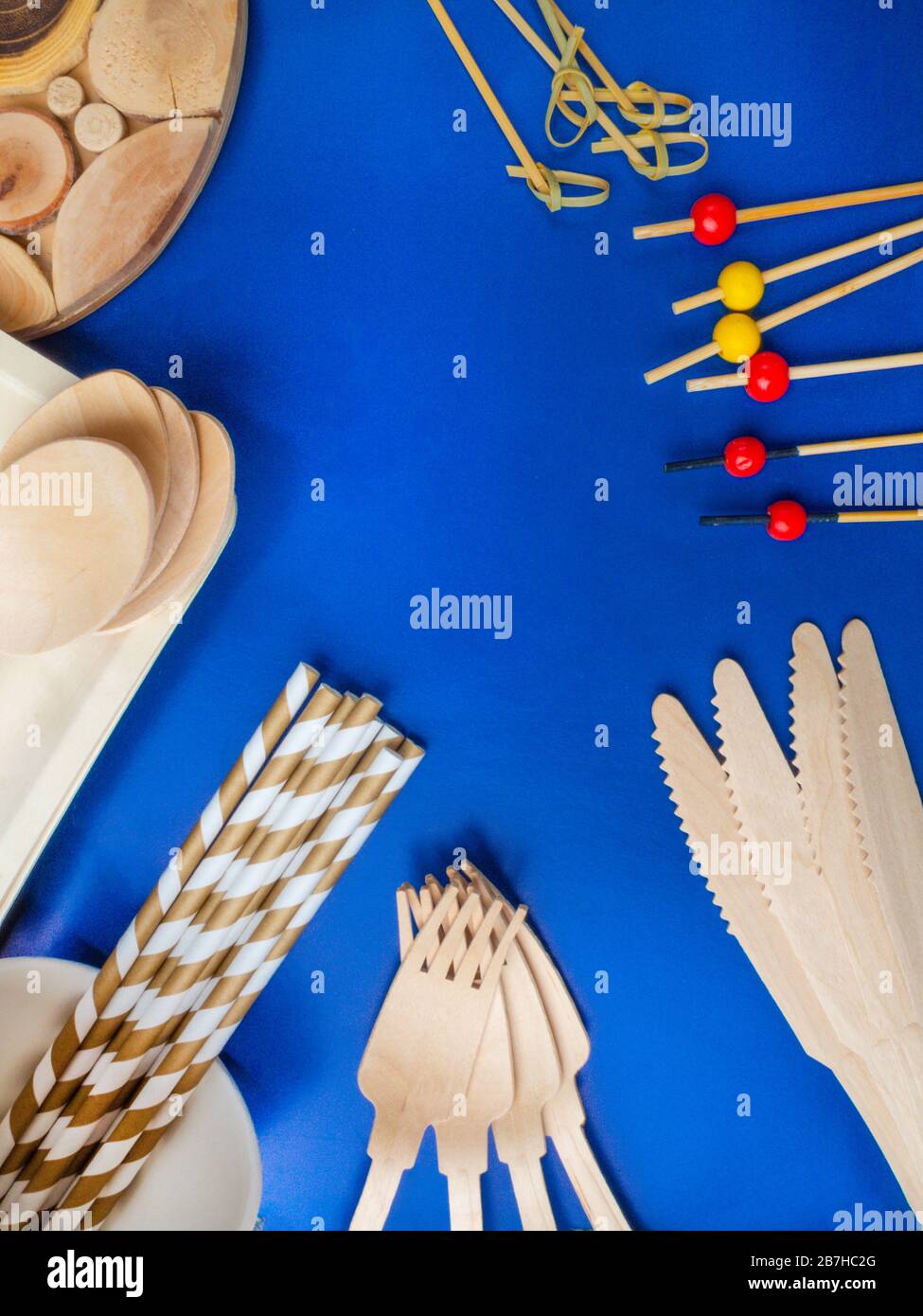 Disposable wooden cutlery on blue color background, drink tube, spoon ...