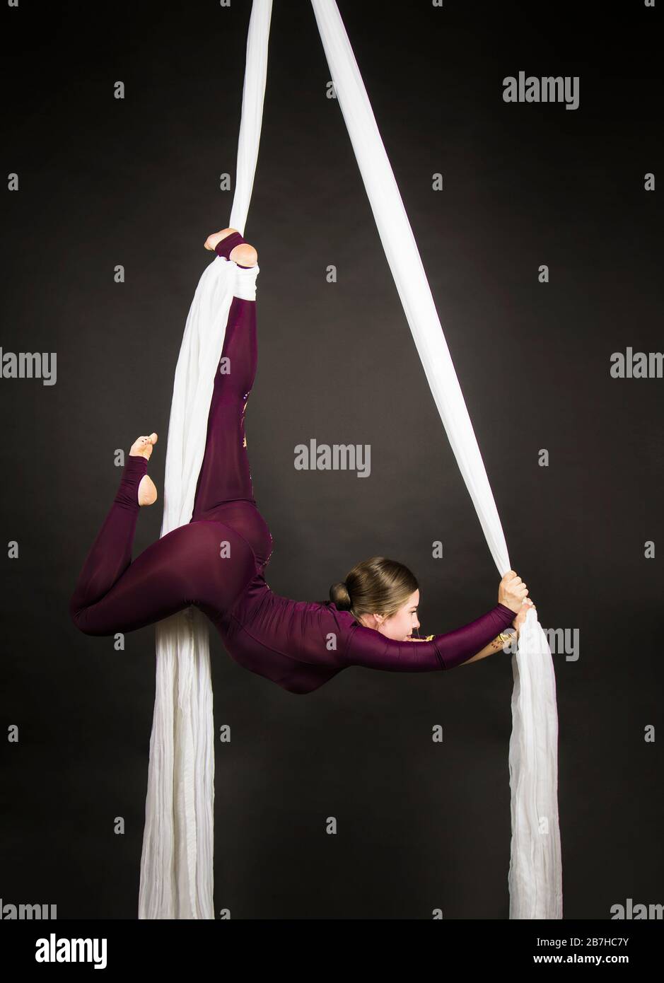 Sporty woman in a Burgundy suit performs gymnastic and circus exercises ...