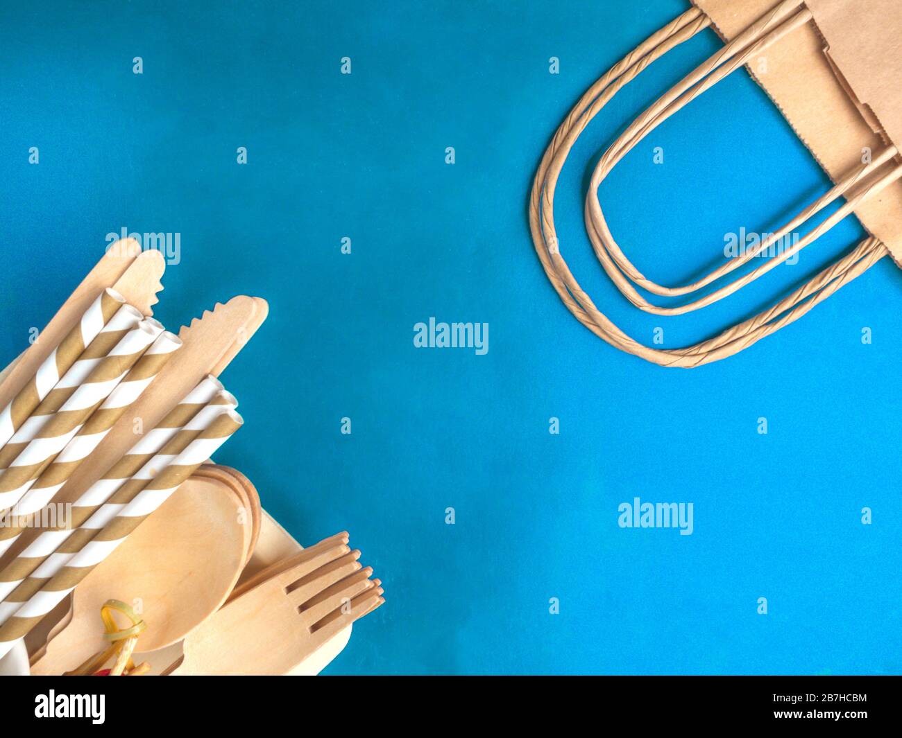 Disposable wooden cutlery on blue color background, drink tube, spoon ...