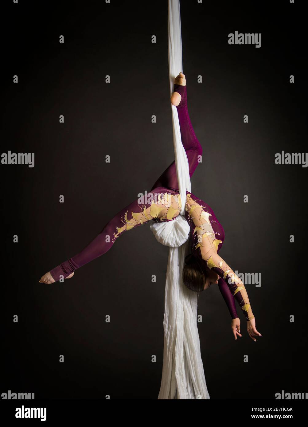 Sporty woman in a Burgundy suit performs gymnastic and circus exercises ...