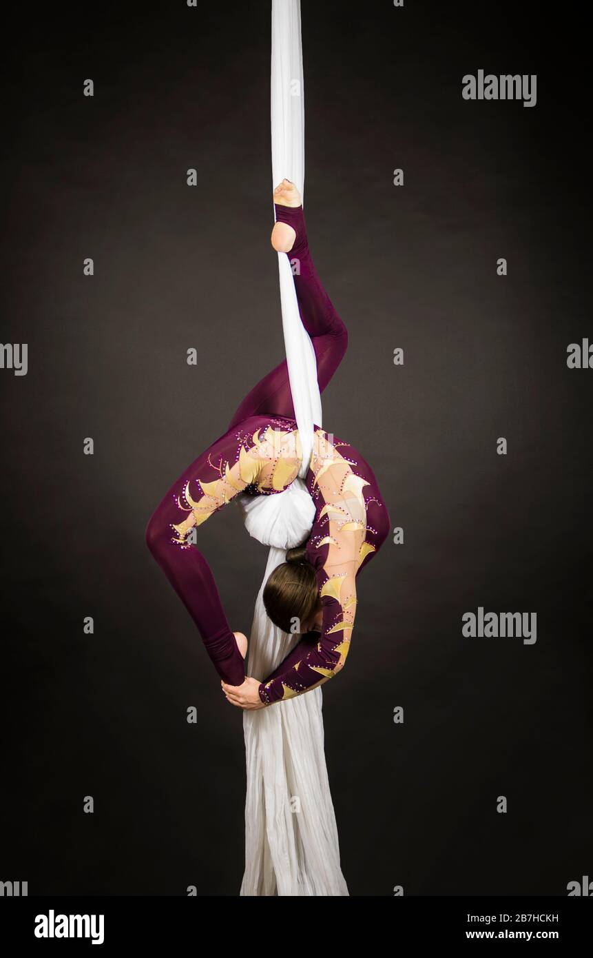 Sporty woman in a Burgundy suit performs gymnastic and circus exercises ...