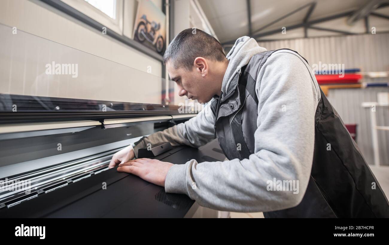 Electrical engineer operator repairs large premium industrial printer ...