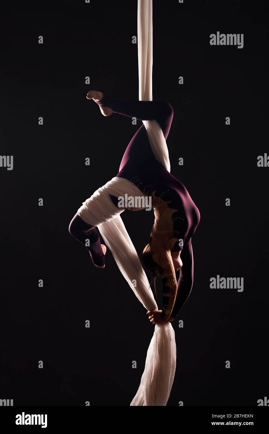 Sporty woman in a Burgundy suit performs gymnastic and circus exercises ...