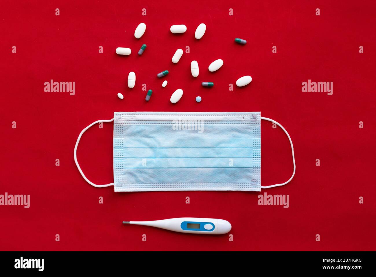 Protective face mask, thermometer and pills on red background. Virus ...